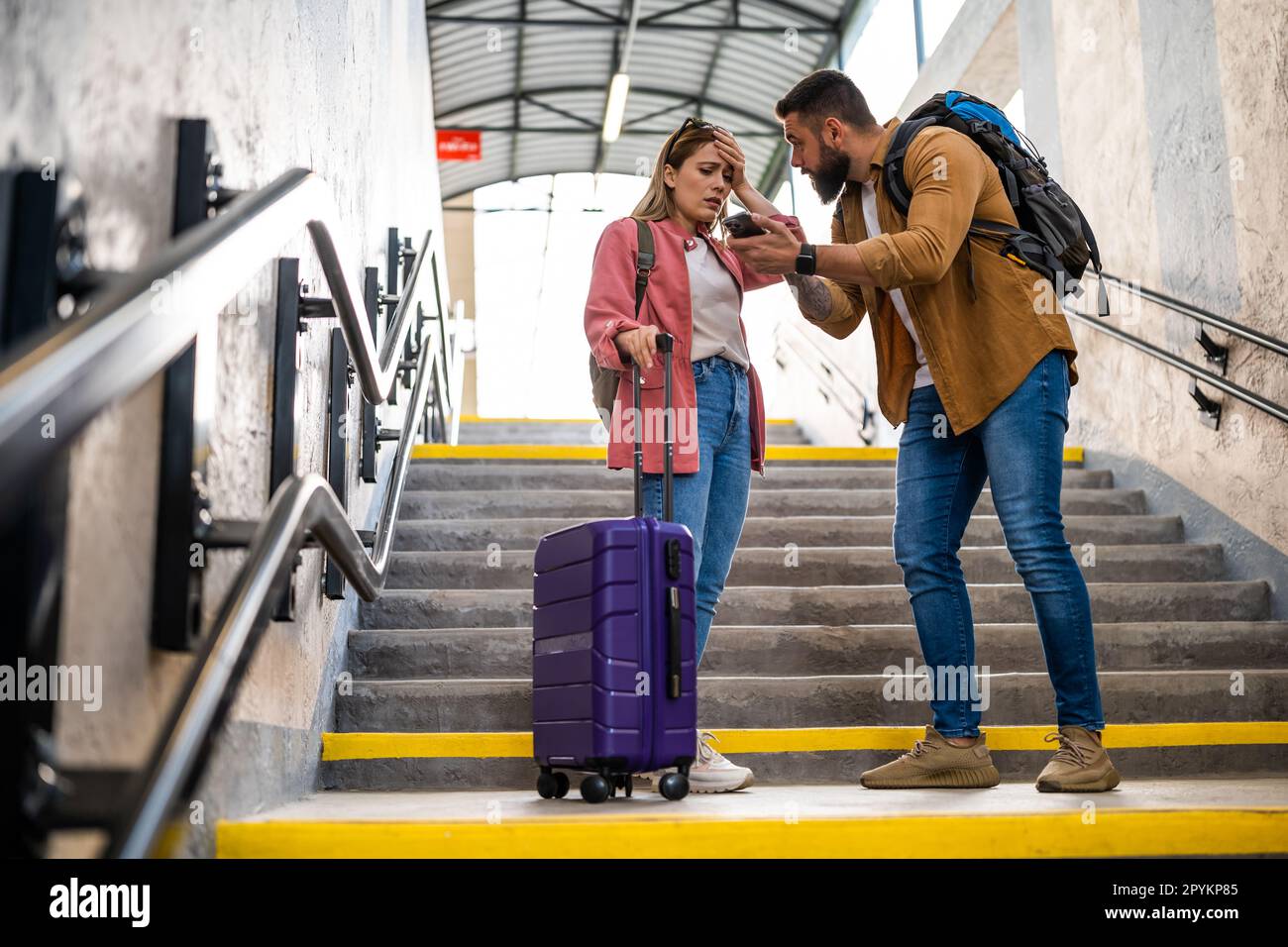 Adult couple missed the departure of the train. The are arguing at at ...