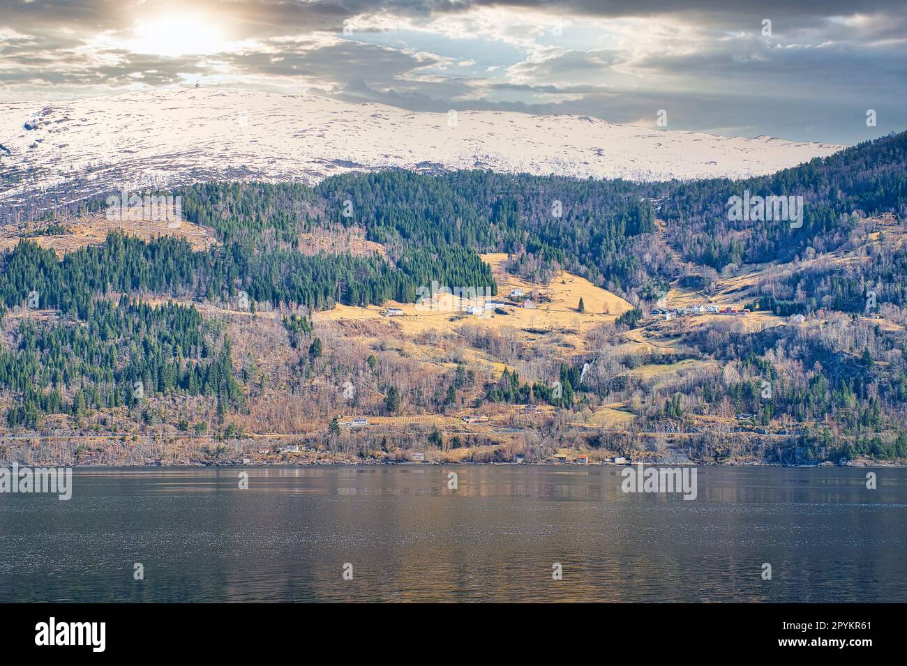 Fjord with snow covered mountains on horizon and dramatic sky. The ...