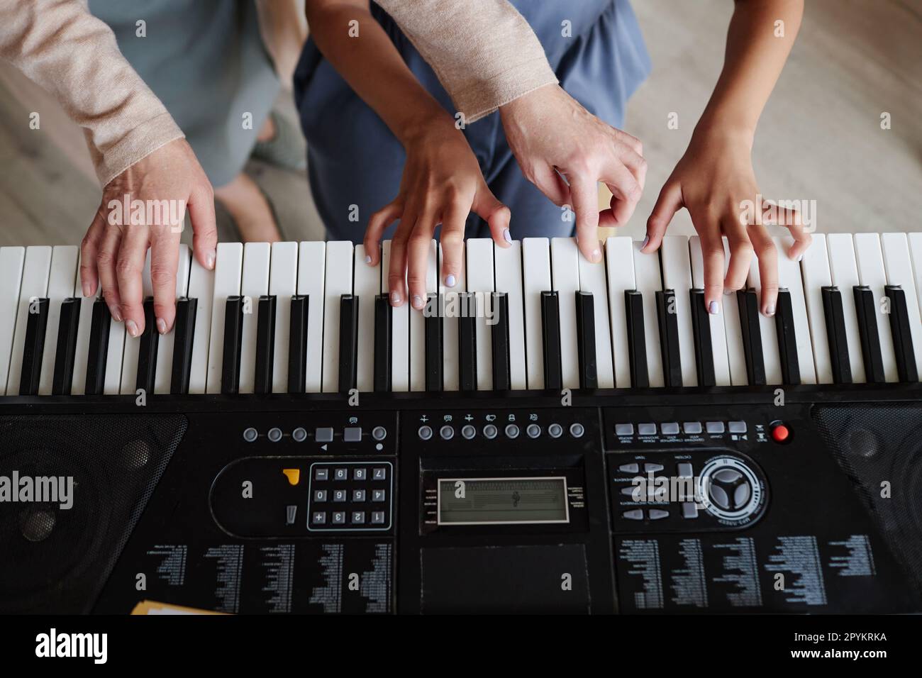 Top view of student learning to play piano together with teacher during ...