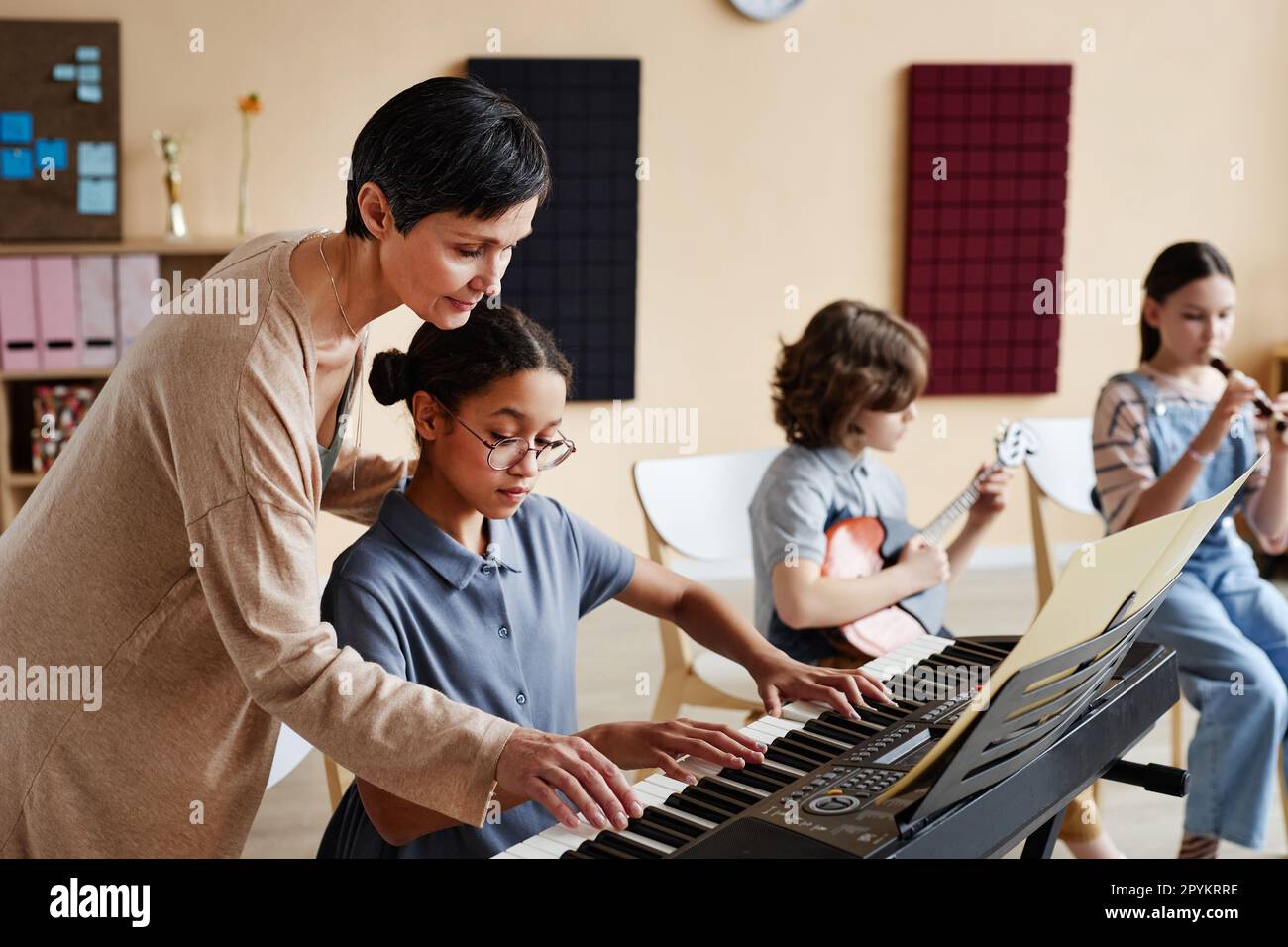 Professional teacher learning children to play musical instruments in ...