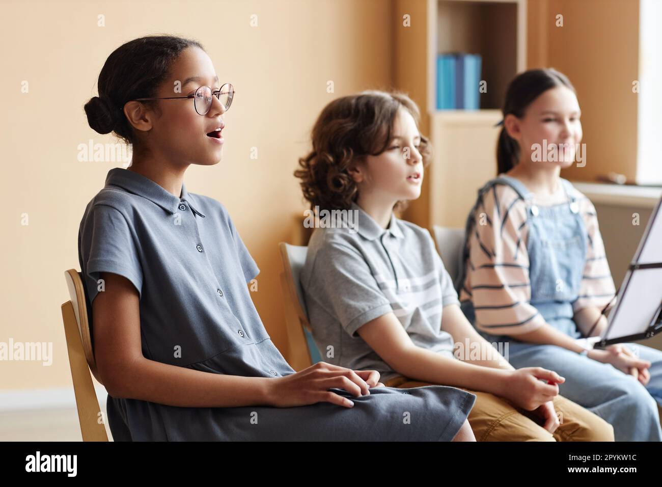 Group of children sitting in class and singing songs in choir during ...