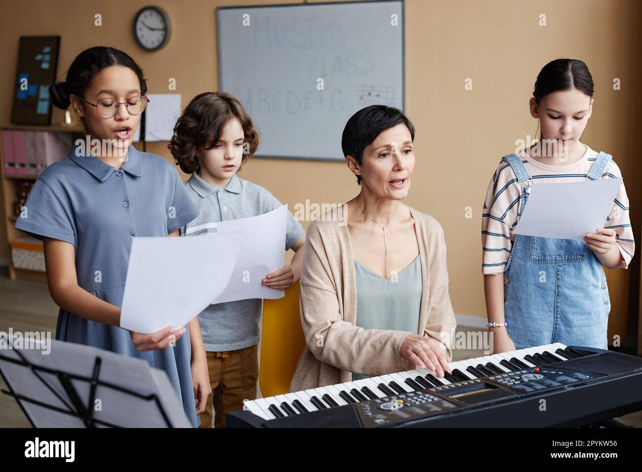 Group of children singing songs together with teacher while she playing ...