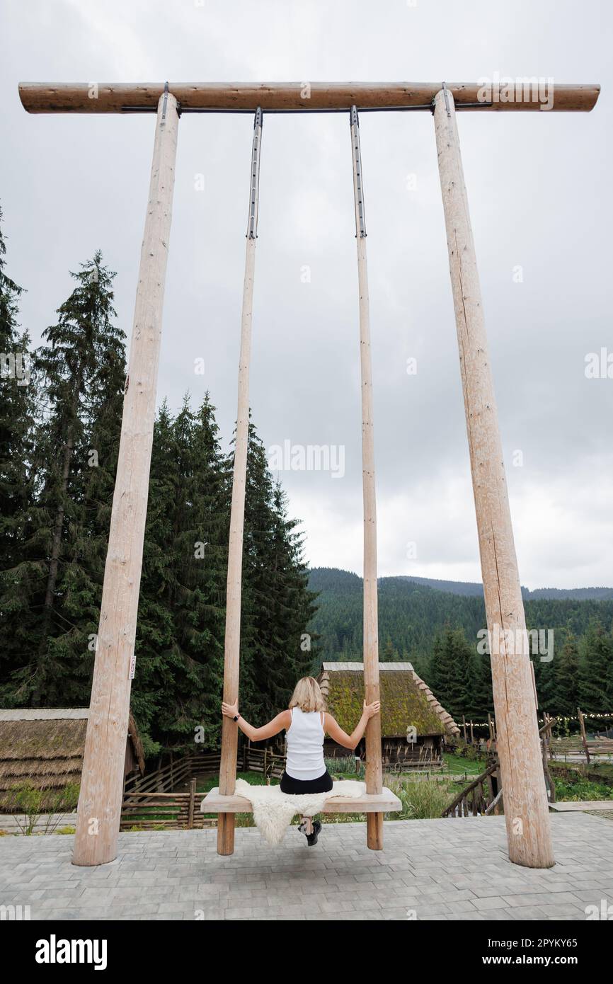A woman sits on a huge swing and contemplates a beautiful view of the ...