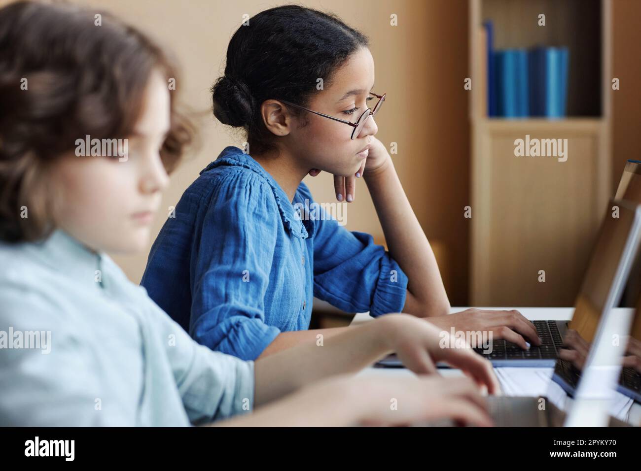 School children concentrating on work on computers while sitting at ...