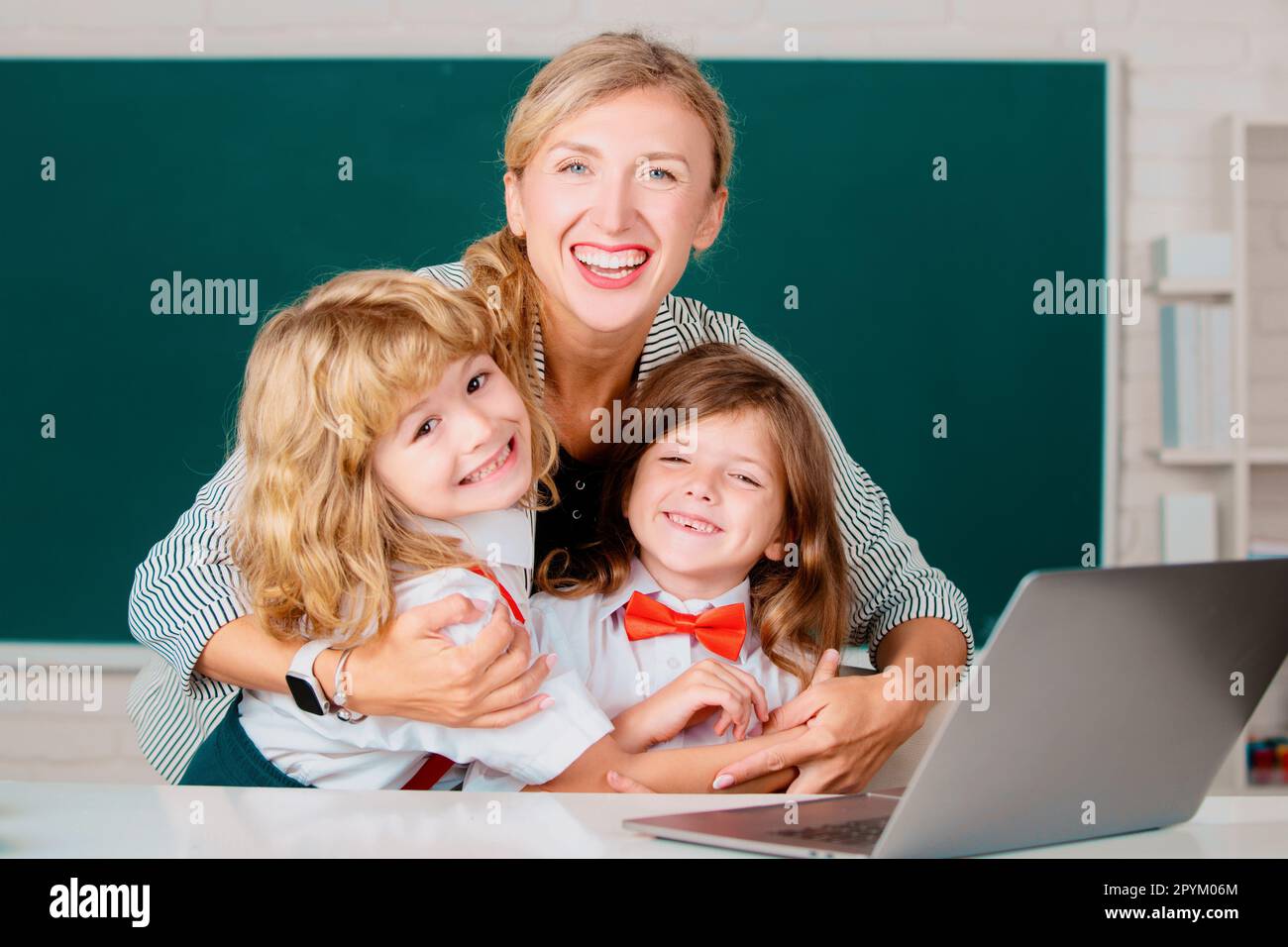 Happy school kids and teacher learning study in class. Teacher helping ...