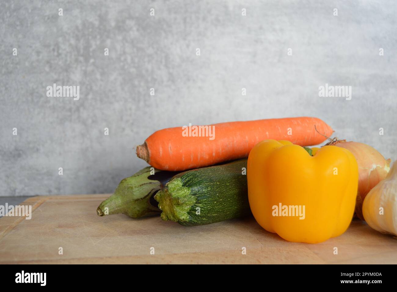 Fresh and colorful vegetables on a light wooden board in a kitchen with ...