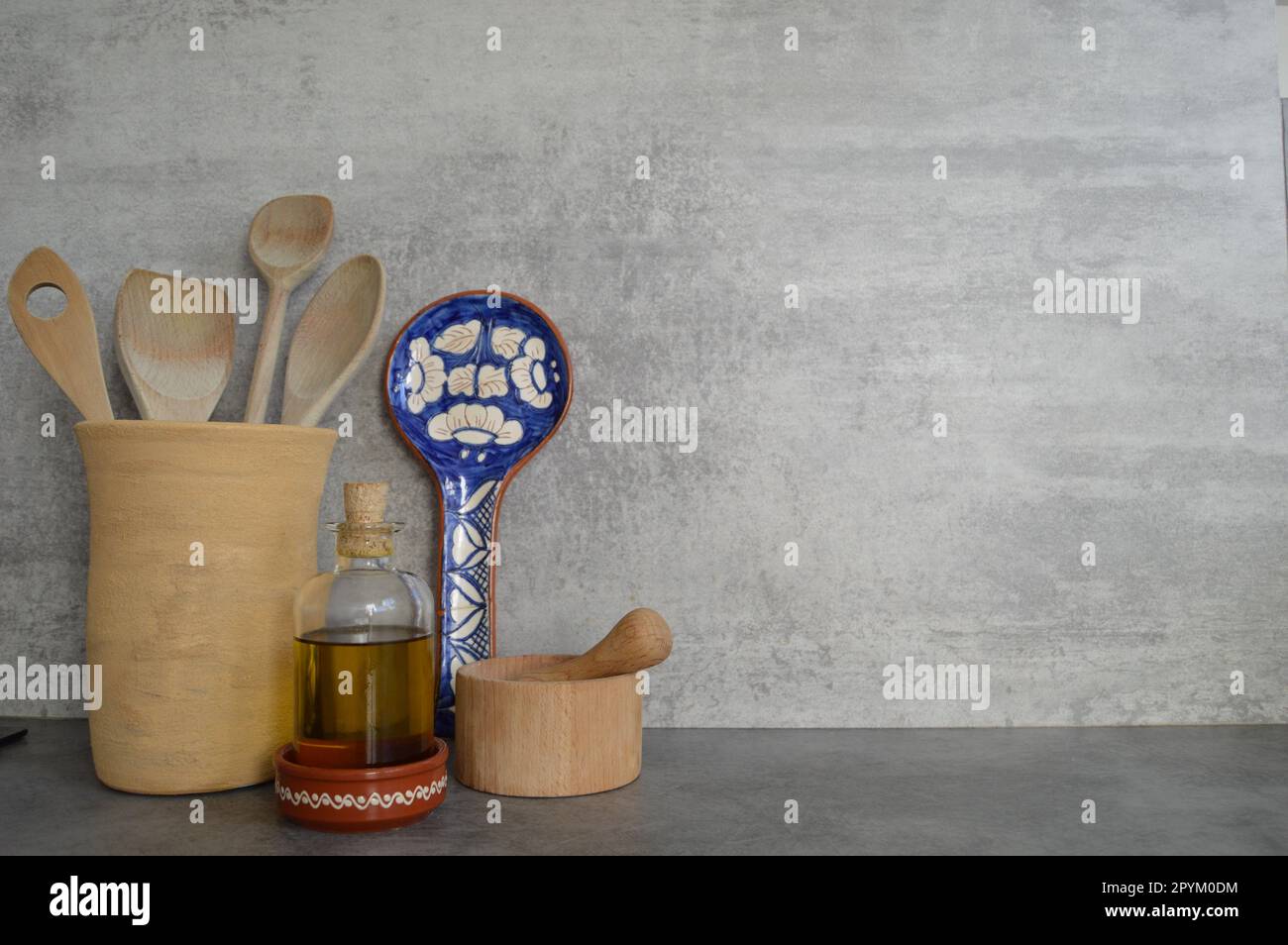 Vase with wooden spoons for cooking with a jar of olive oil and a ...