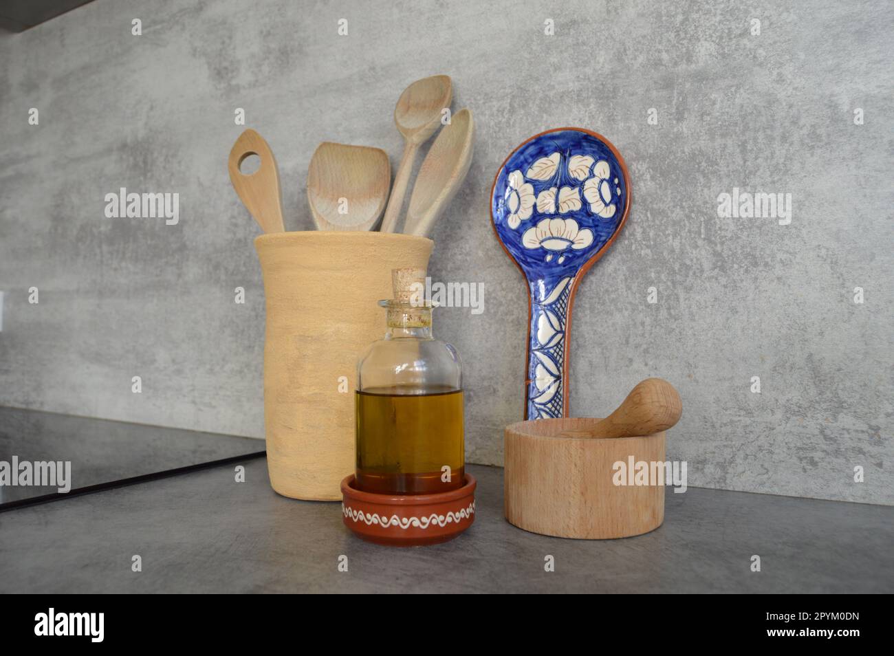 Induction hob with wooden spoons, olive oil, a spoon holder and a ...