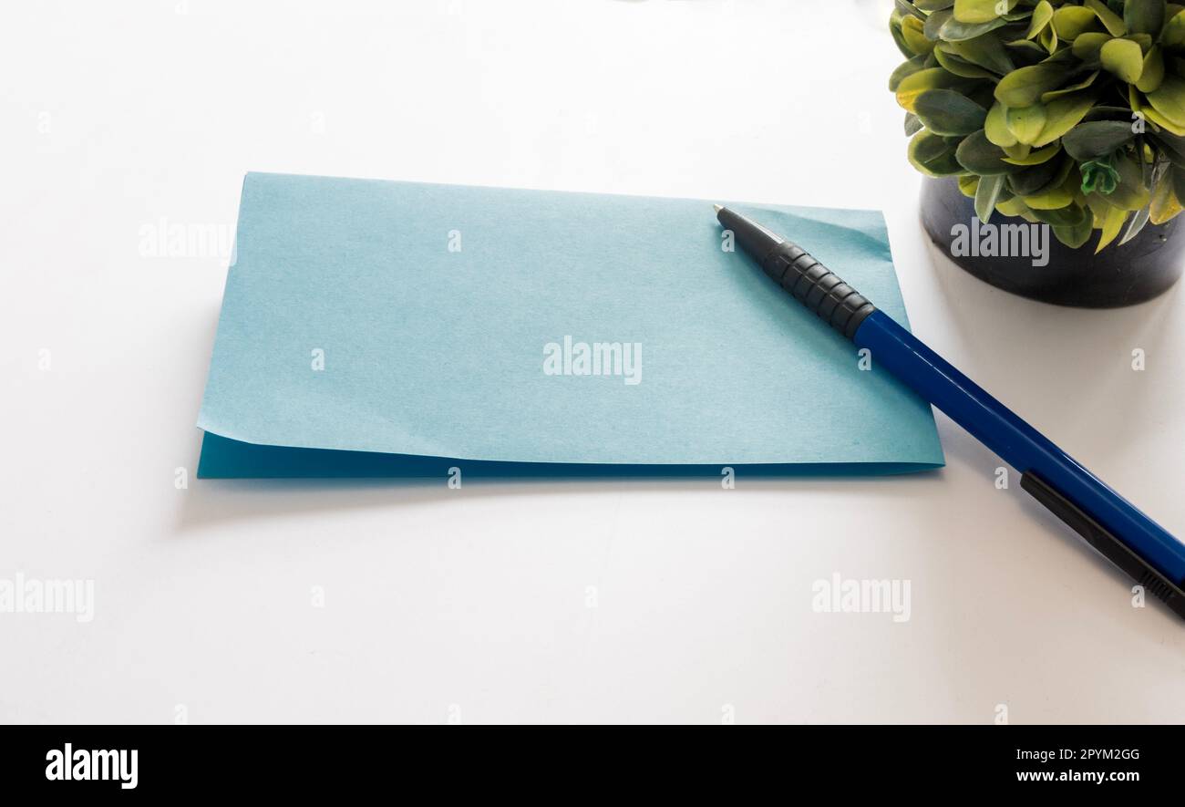 A blank blue paper with pen and green flower on white background with ...