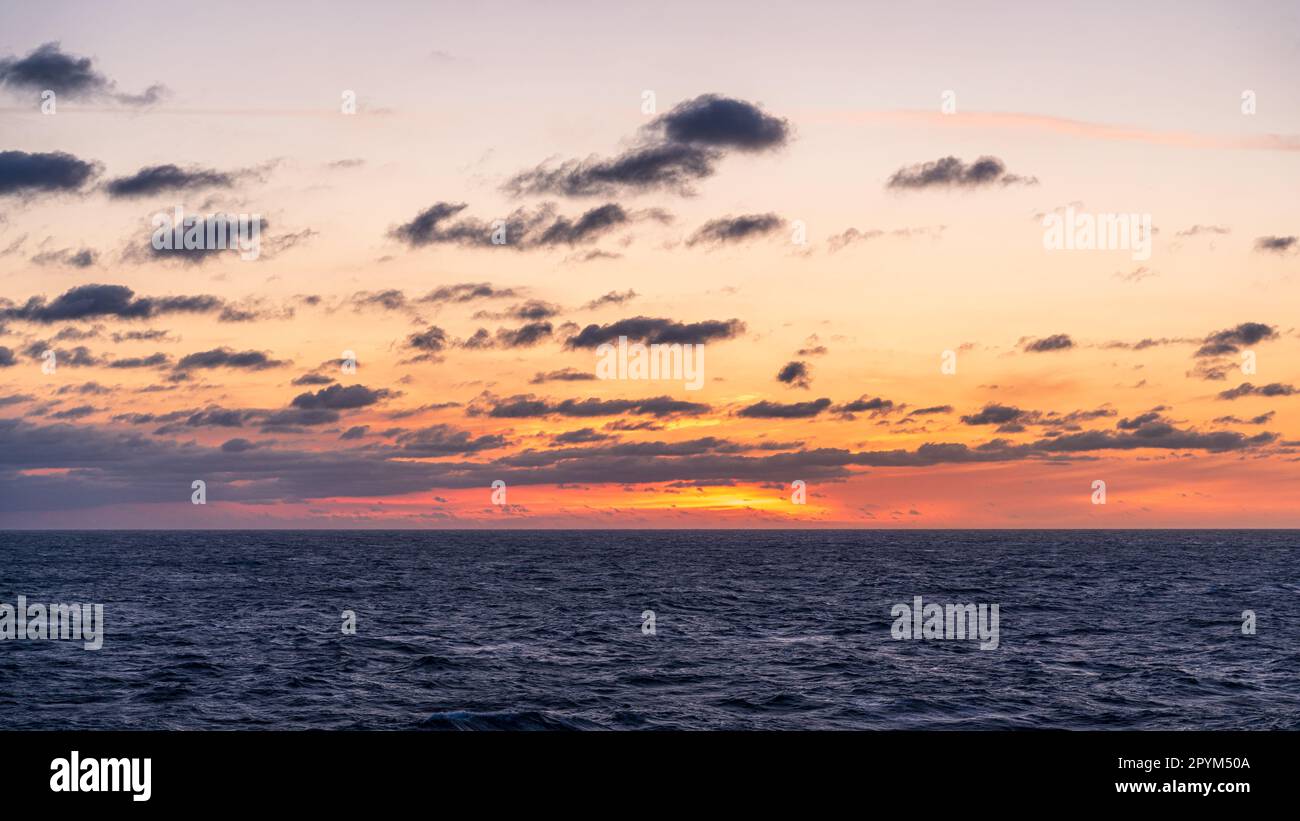A stunning image of a sunrise over an ocean with dark clouds in the ...