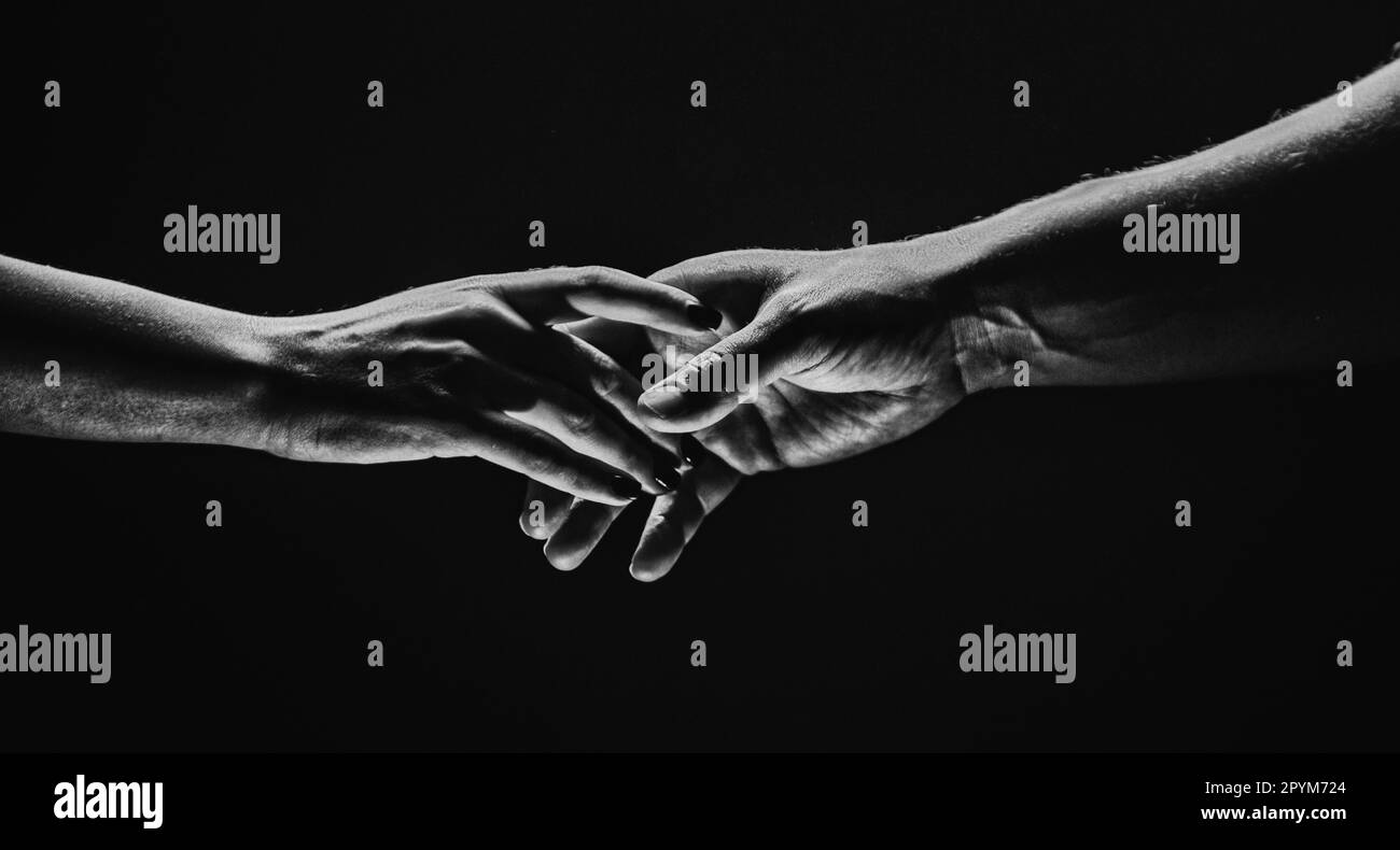 Two hands stretch each other, black background. Couple in love holding ...