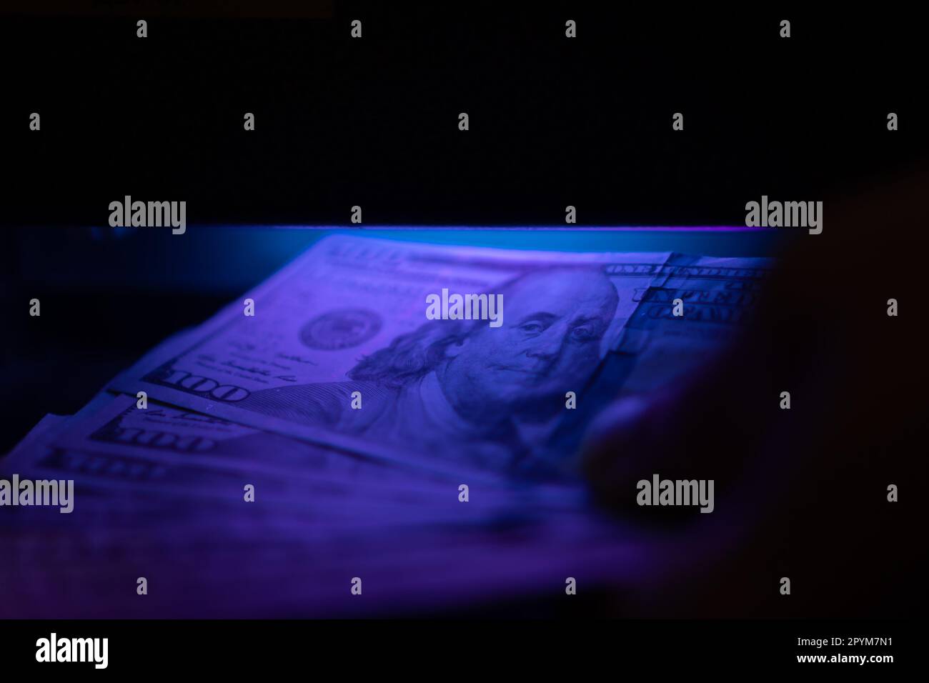 Close-up of dollars under an ultraviolet lamp. Inspection of a dollar ...
