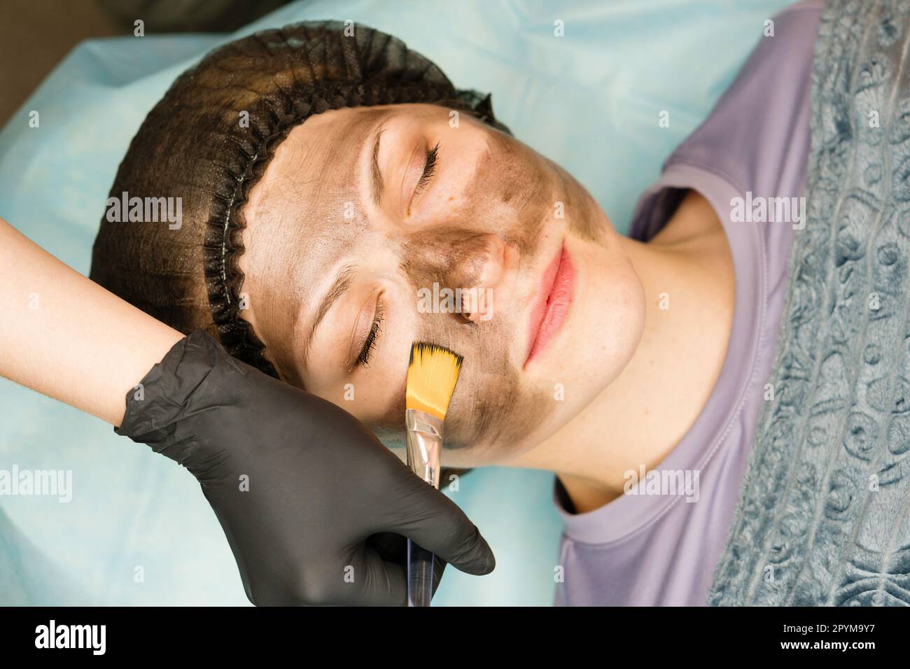 Cosmetologist applies carbon nanogel of client's face. Preparing for ...