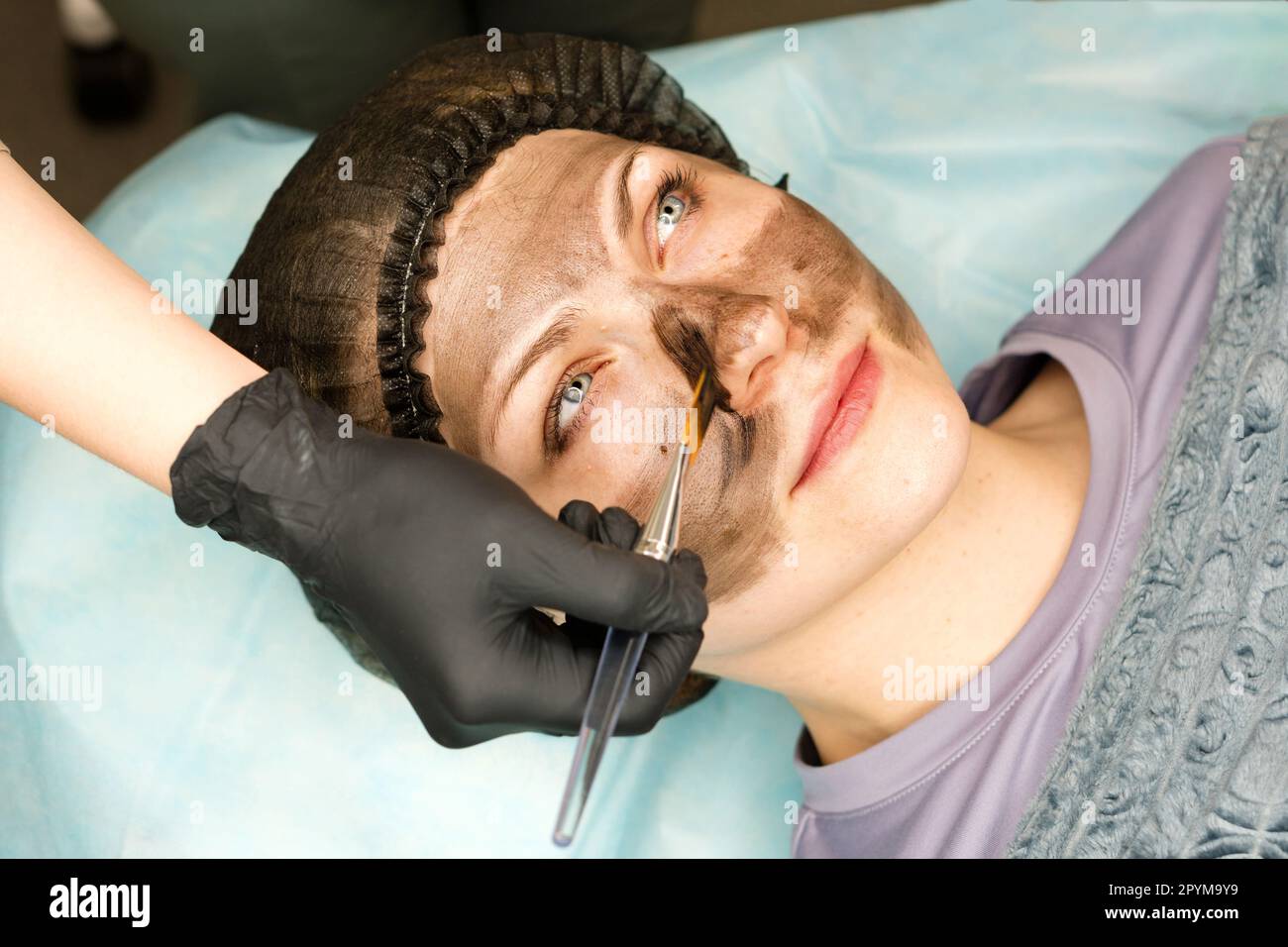 Cosmetologist applies carbon nanogel of client's face. Preparing for ...