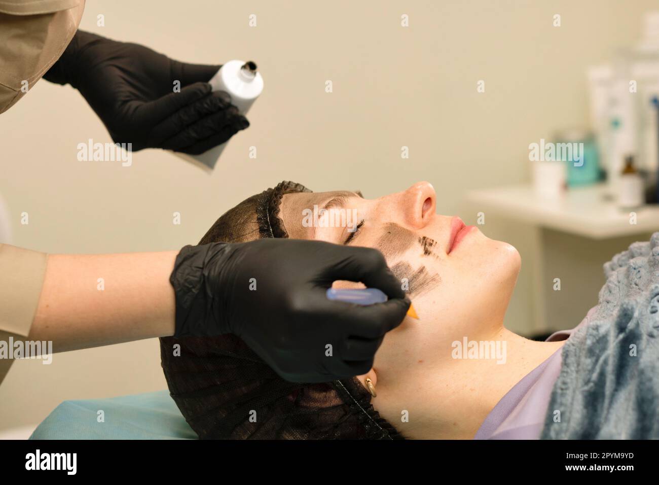 Cosmetologist applies carbon nanogel of client's face. Preparing for ...