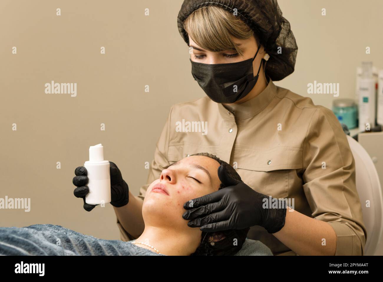 Beautician applying cosmetic acne preparation on face teen girl in ...