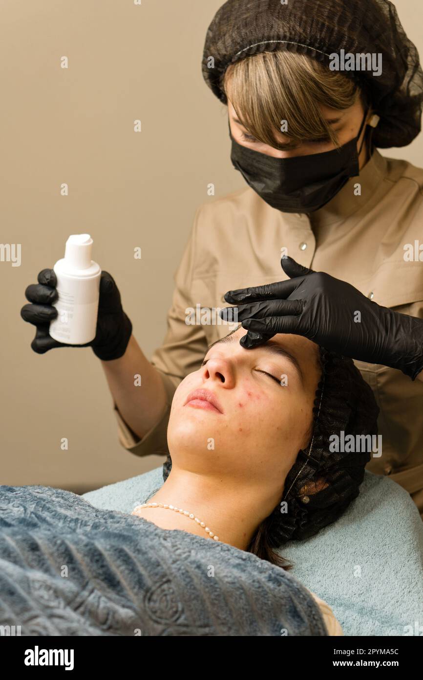 Dermatologist applying cosmetic acne preparation on face teen girl in ...