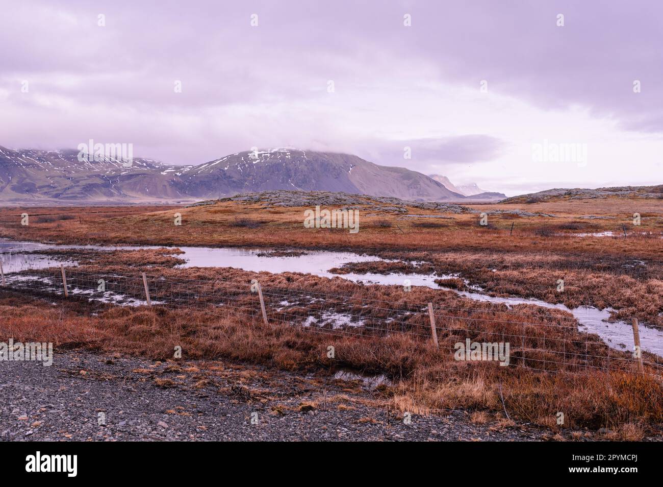 A stunning landscape of small mountains by a body of water, with snow ...