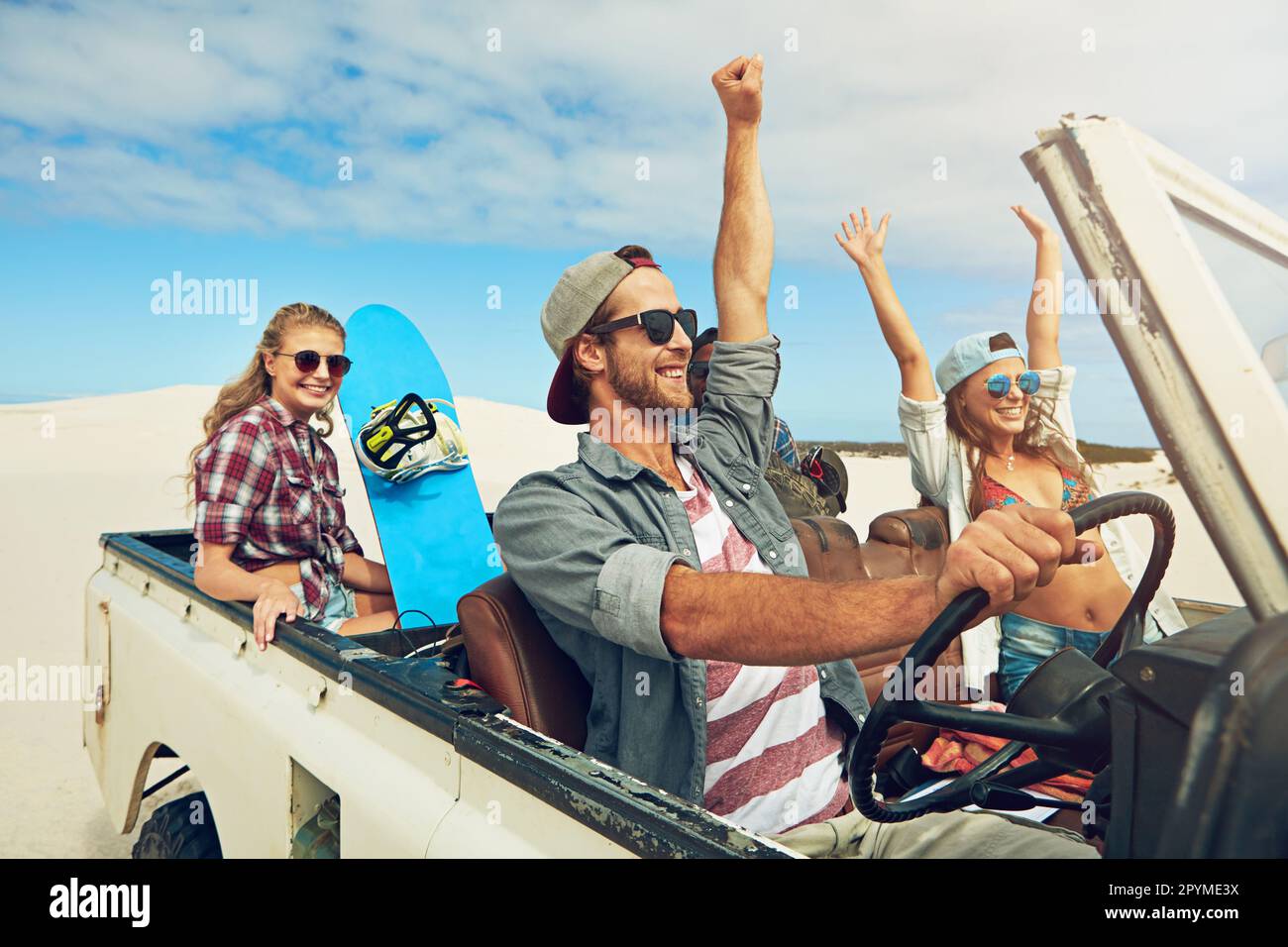 Riding the sandy slopes of the desert. a group of young friends going ...