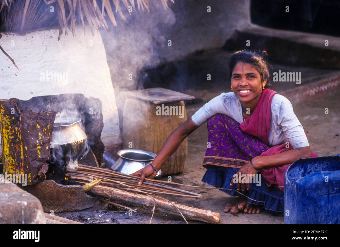 A woman cooking using a firewood stove in front of her hut, Niligiris ...