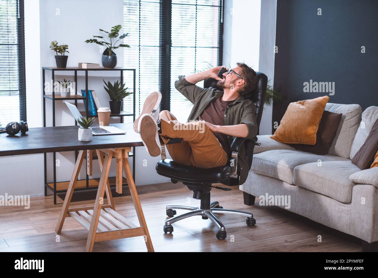 Businessman taking break in office and having conversation on phone ...
