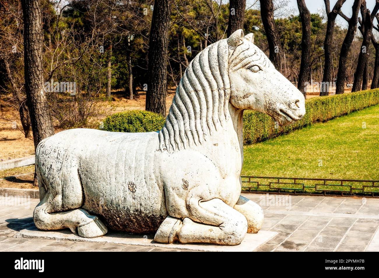 An ancient white stone statue of a kneeling horse along the well ...