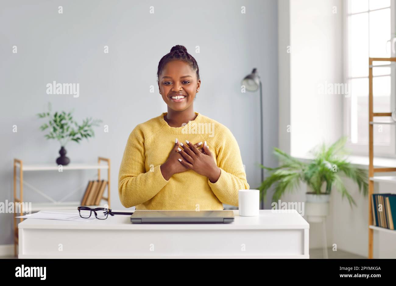 Happy young woman holding folded hands on chest Stock Photo - Alamy