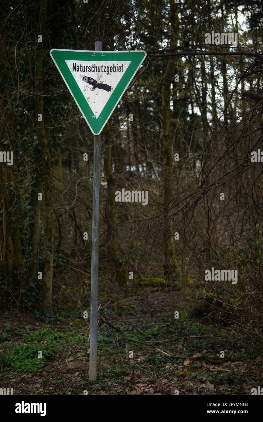 This image portrays a nature reserve sign in a lush green forest in ...
