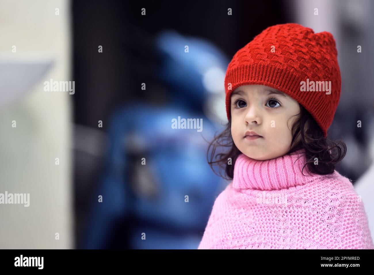 2 years old Indian baby girl wearing red woolen cap and pink poncho ...