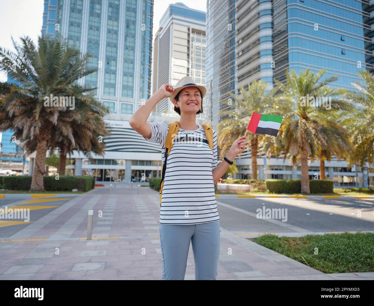 Happy young asian female traveler with backpack and hat with UAE flag ...