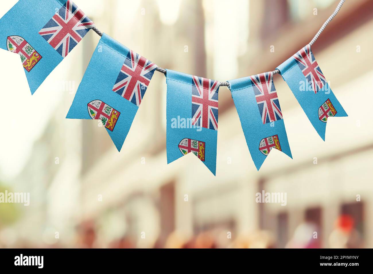 A garland of Fiji national flags on an abstract blurred background ...