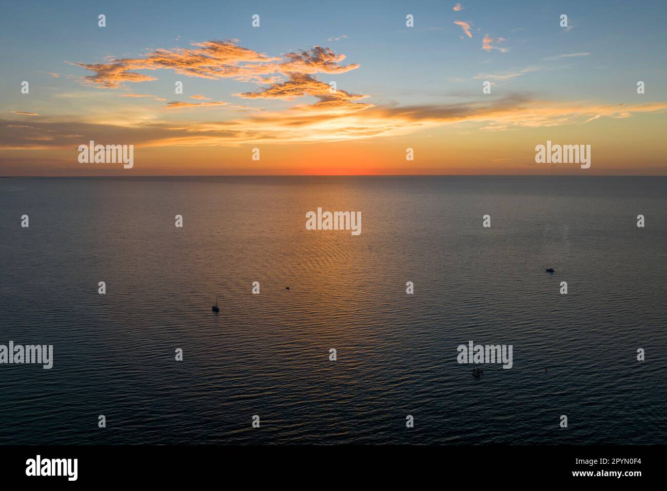 Aerial view of small yachts at sunset floating on sea waves with ripple ...