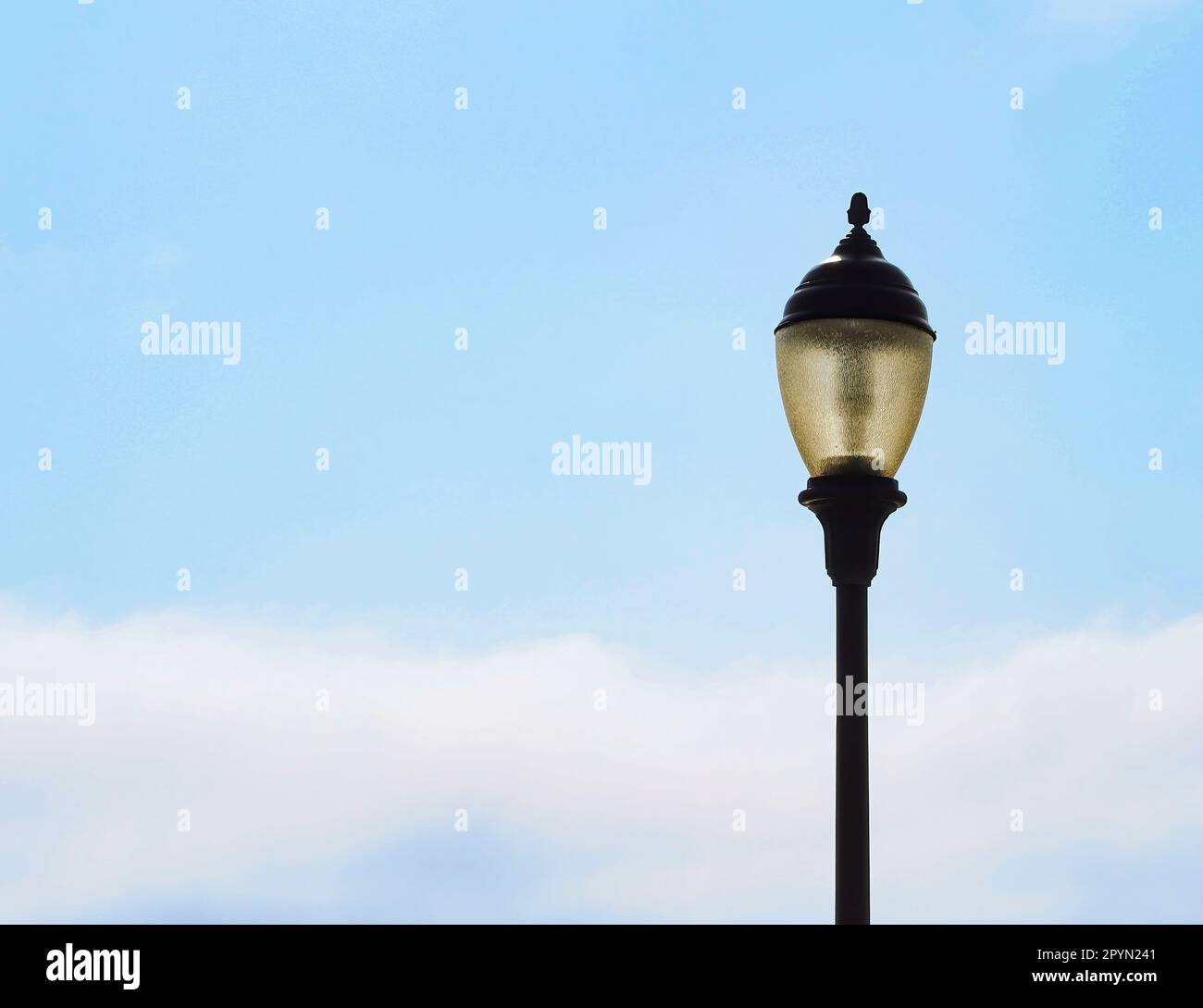 Old-fashioned lamp post street light in daytime against light blue sky ...