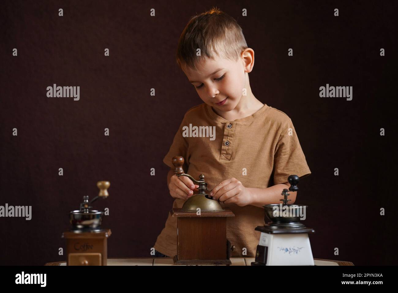 Cute preschool boy grinds coffee in a manual retro coffee grinder with ...