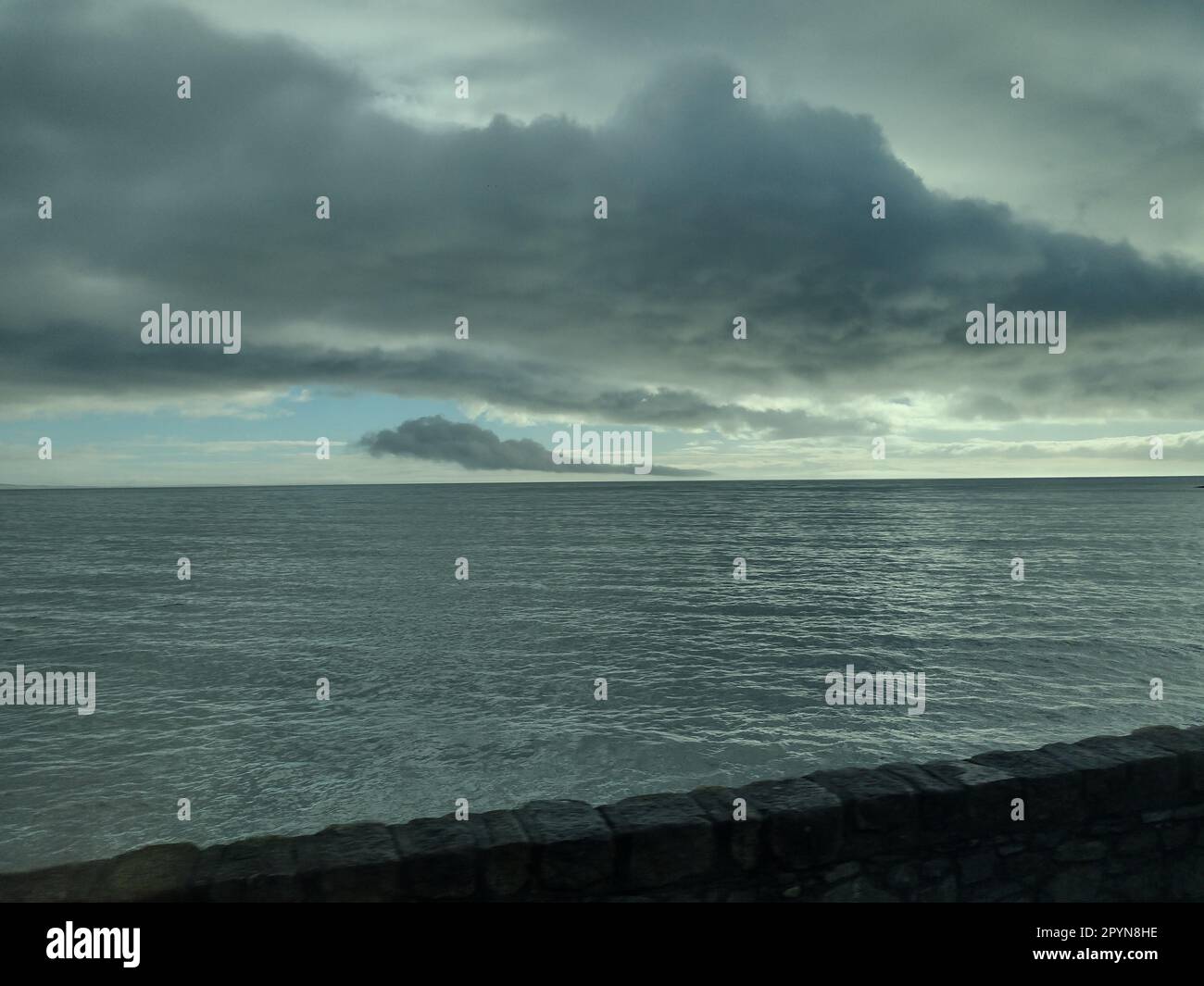 A stunning landscape featuring a body of water with dark storm clouds ...