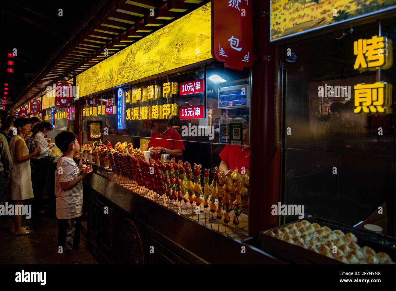 Chinese people buying sweets from a street confectionery at night ...