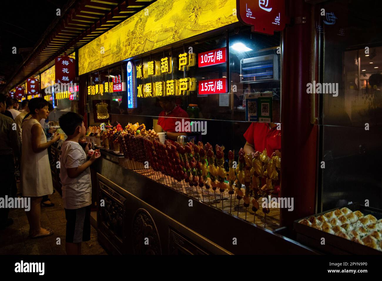 Chinese people buying sweets from a street confectionery at night ...