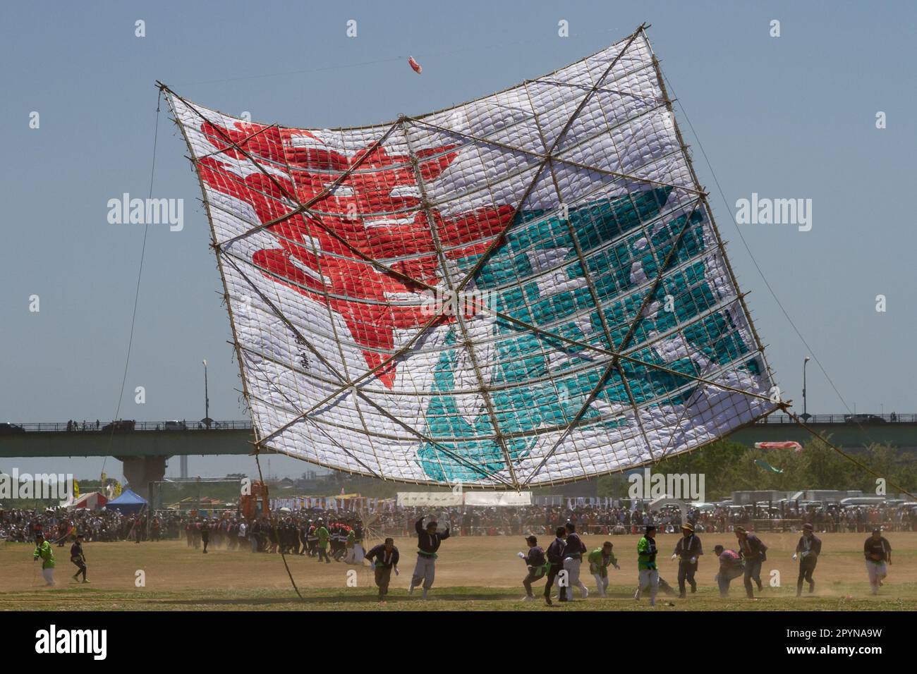 People run as they launch a large kite at the Sagami Giant Kite ...