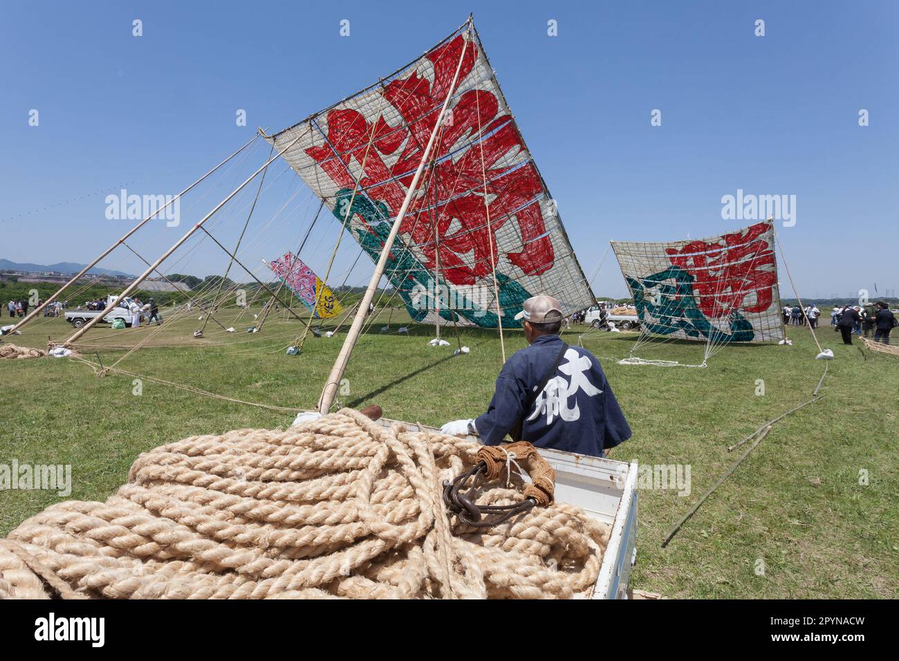 A small minivan carrying ropes in front of large kites on display at ...