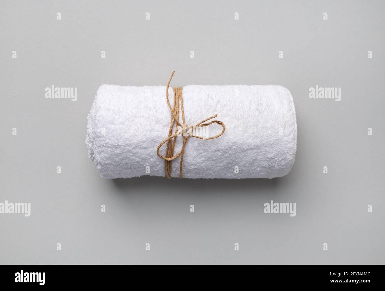 Rolled white towel tied with a rope on gray paper background Stock ...