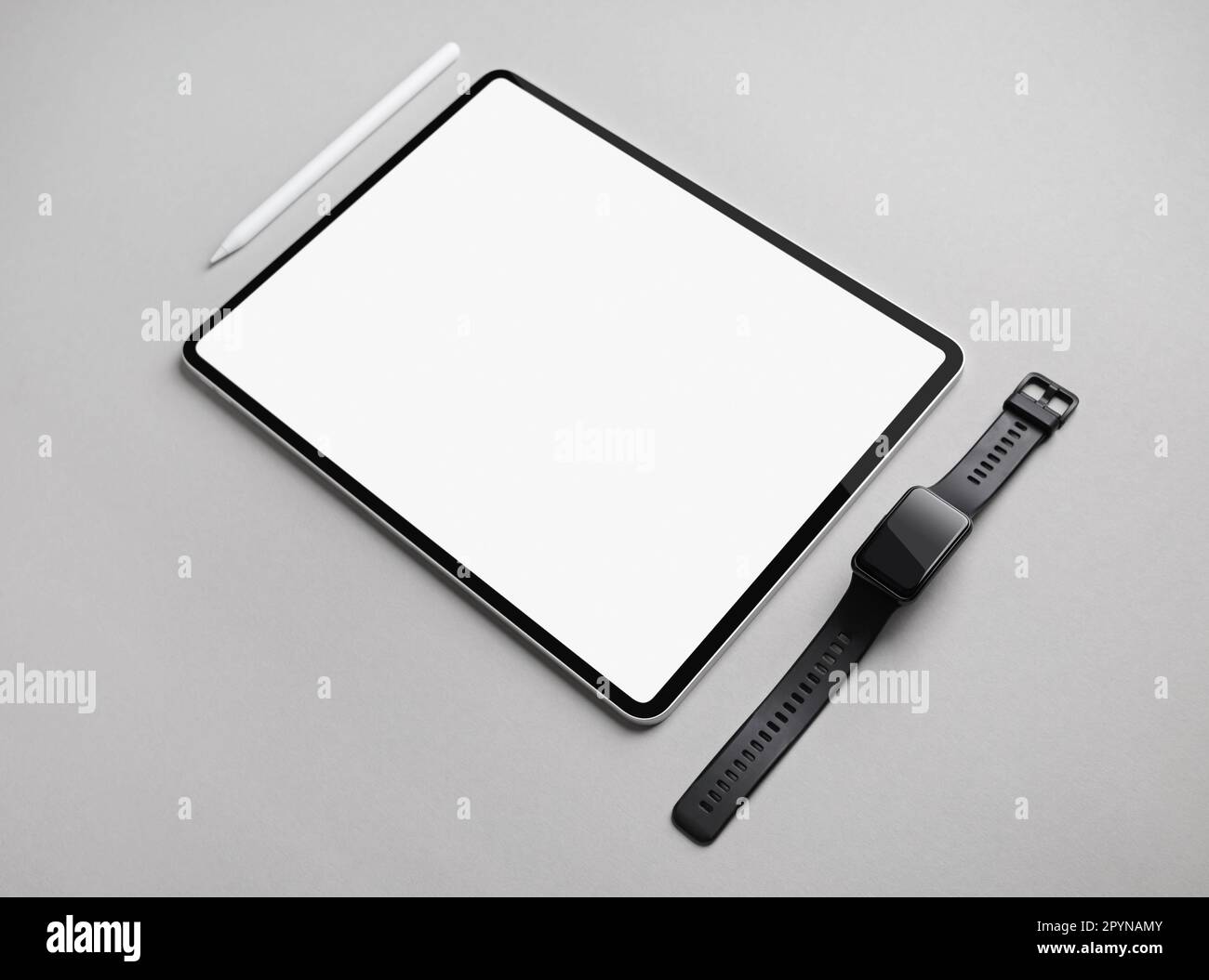 Tablet computer with blank white screen, smart watch and stylus on gray ...