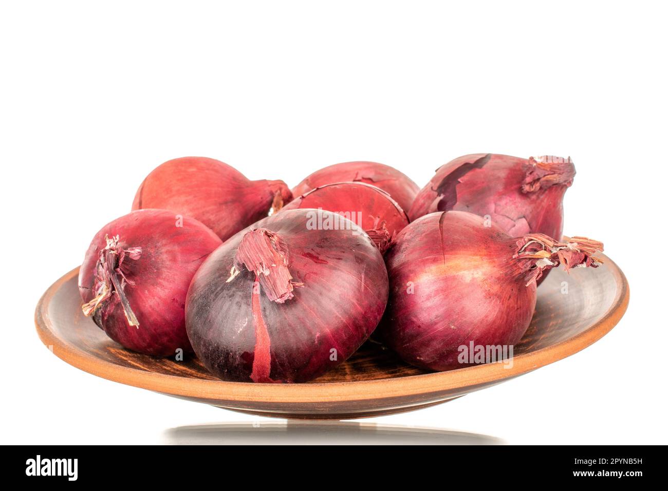Several blue onions on a clay plate, macro, isolated on white ...