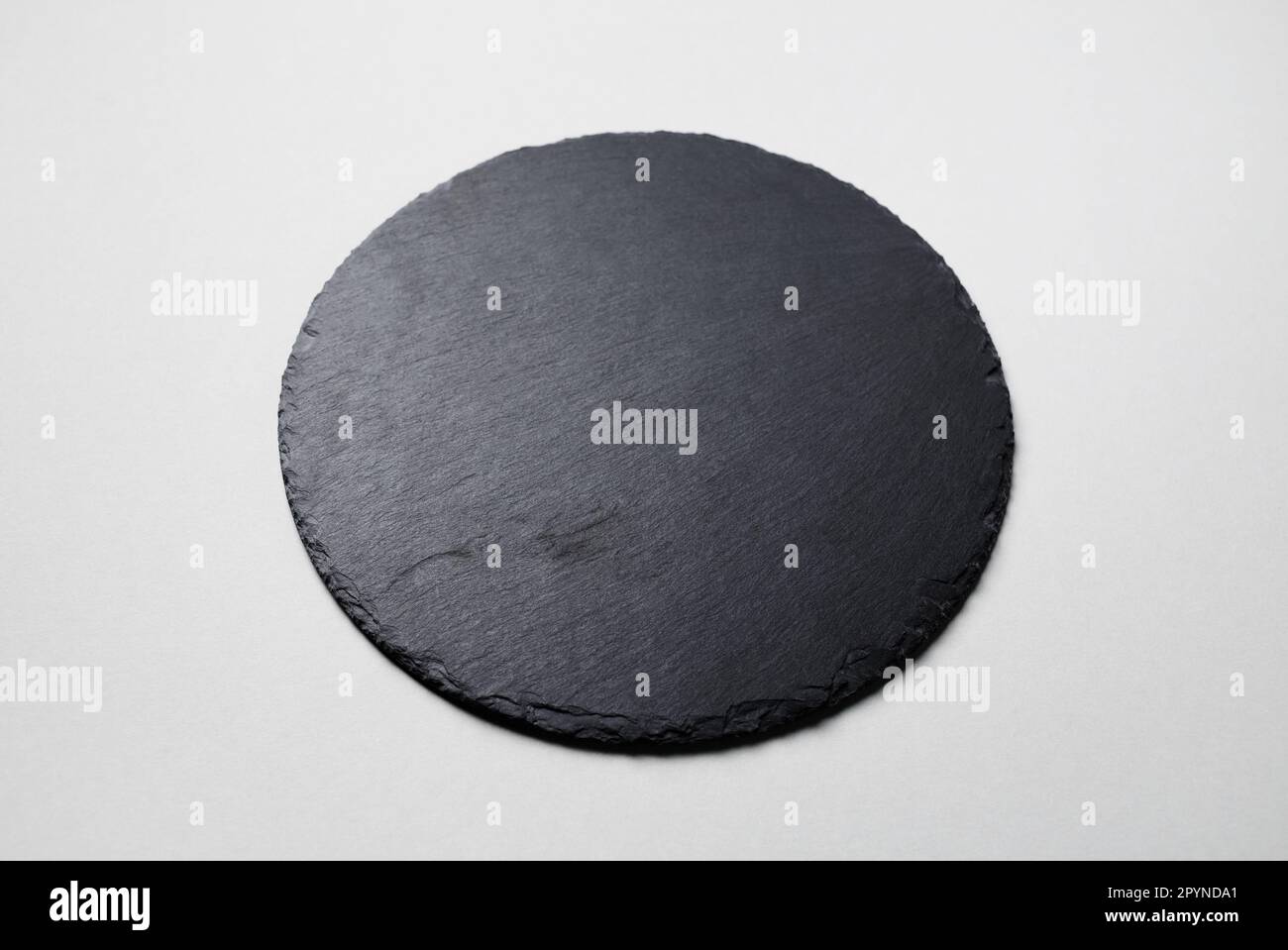 Black round stone slate plate on gray paper background Stock Photo - Alamy