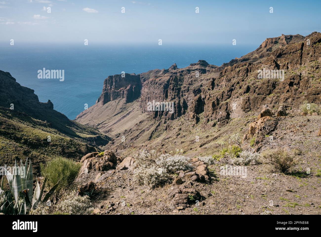 A rocky cliff and desert area next to the ocean with blue water in the ...