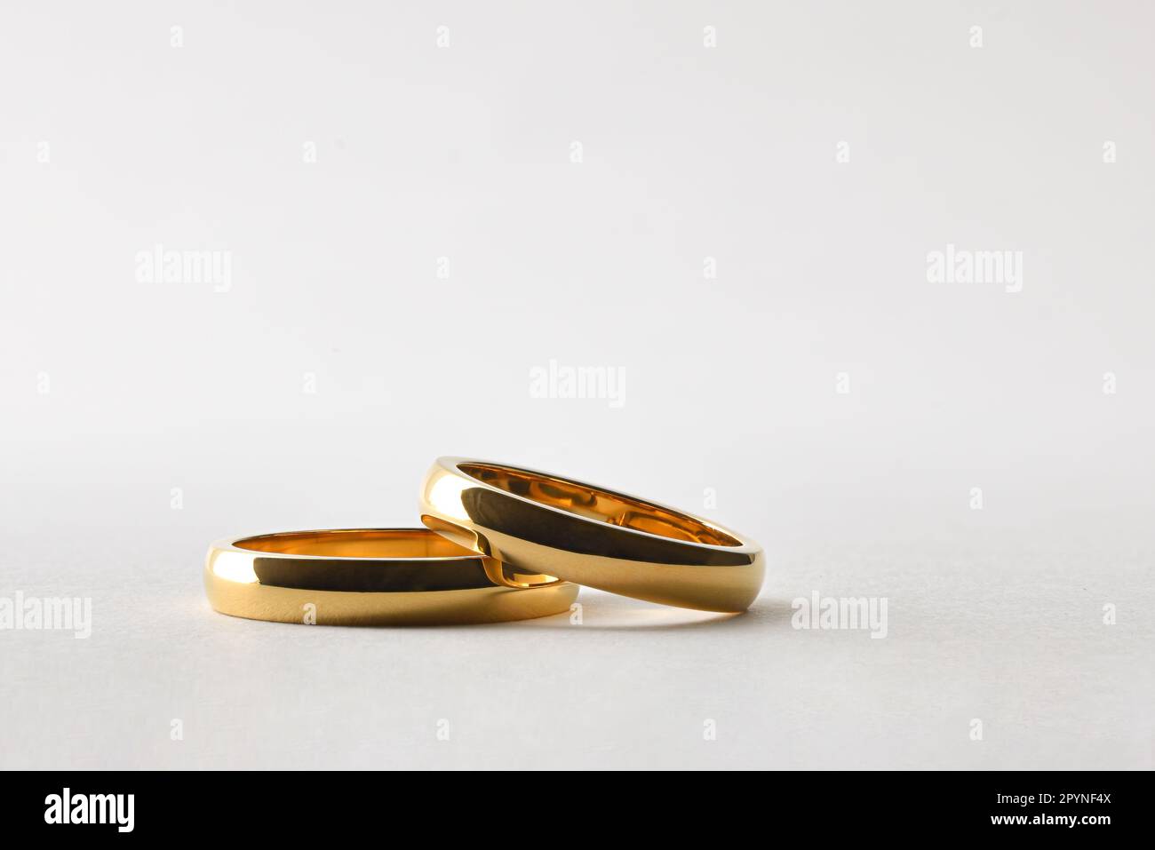 Detail of two gold wedding rings lying one on the other on white ...