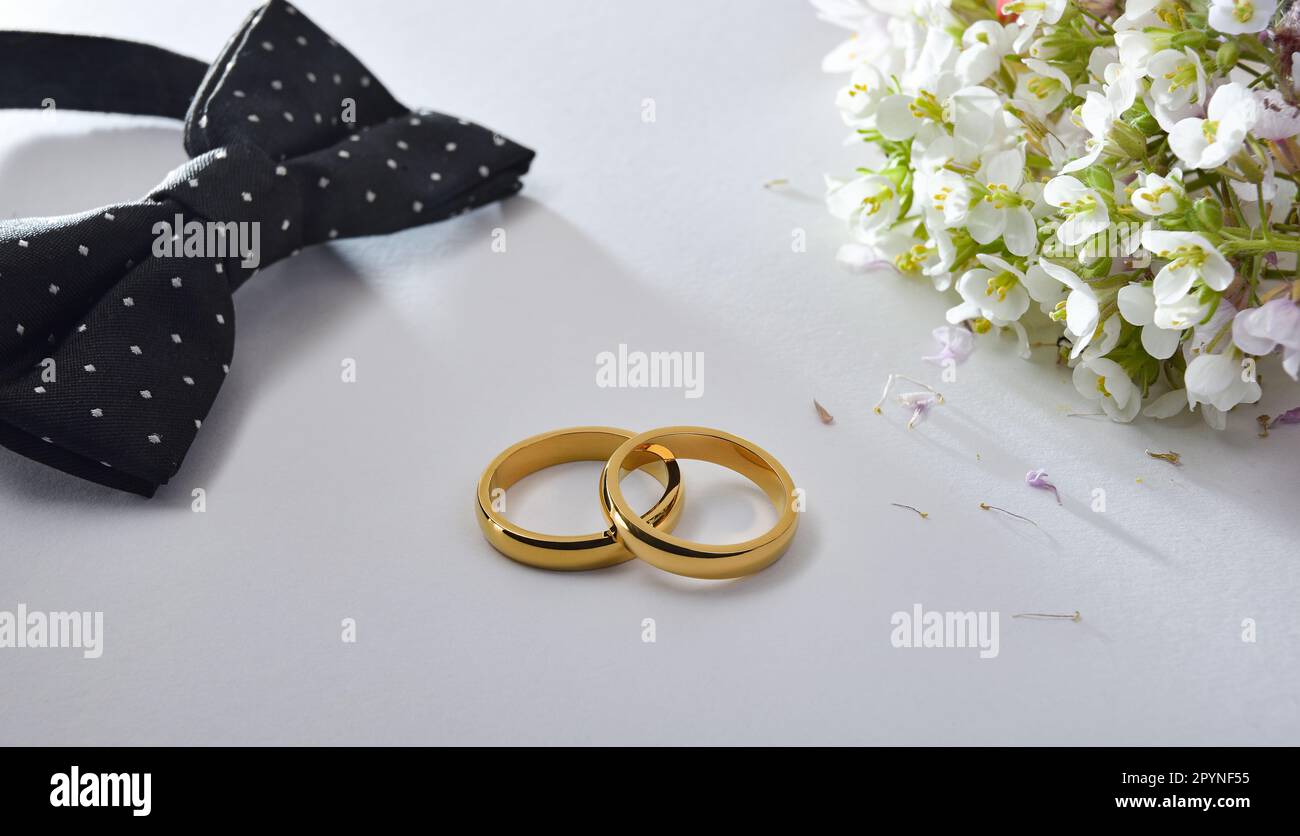 Wedding concept with gold rings in the center on white table and black ...