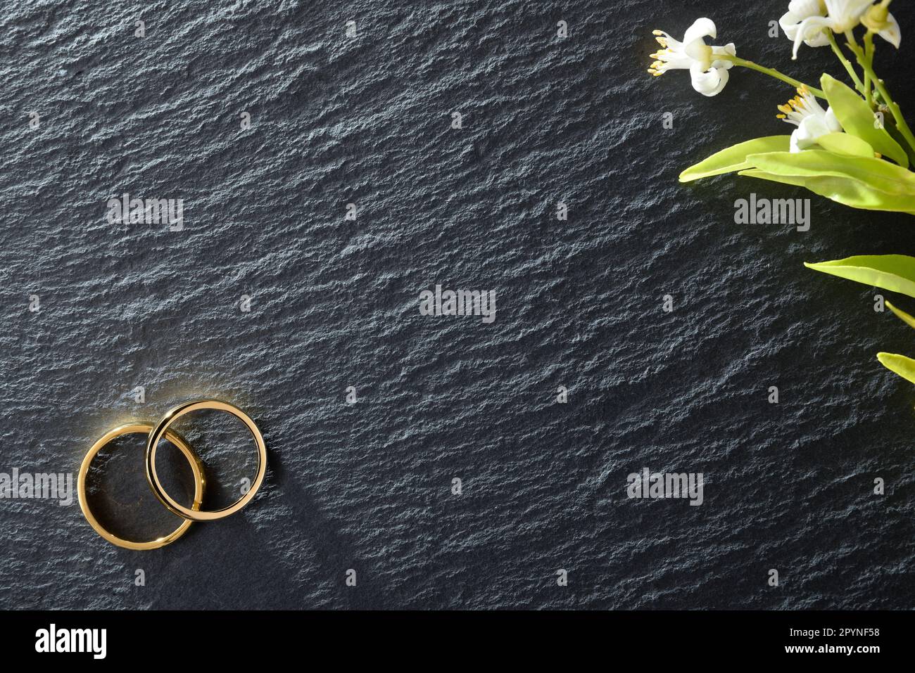 Slate stone background for marriage announcement with two gold rings in ...