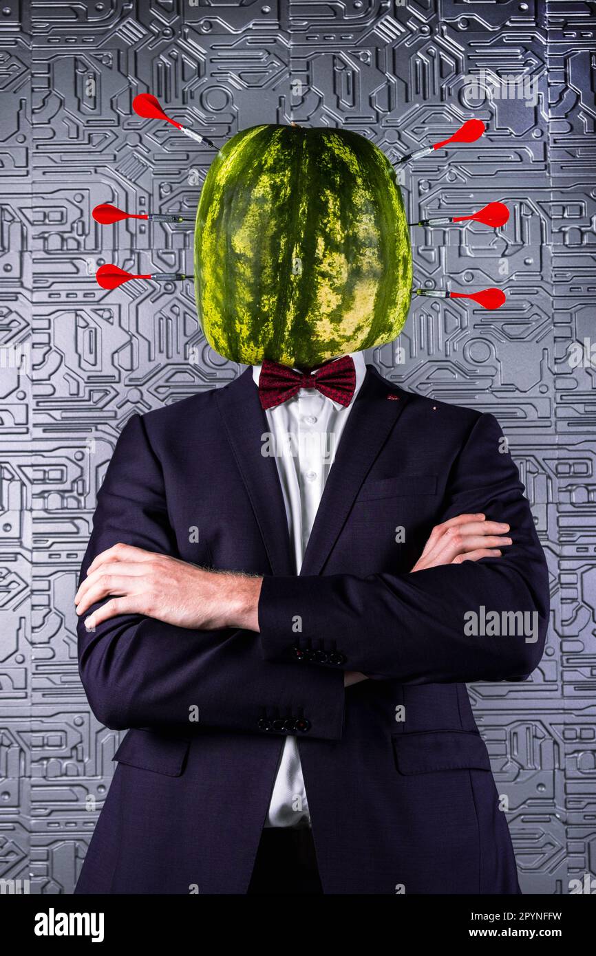 A man with a watermelon-shaped head. Darts are inserted into a ...