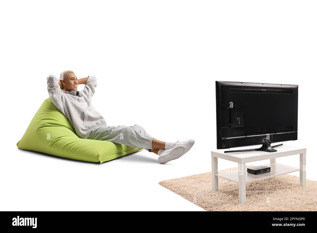 African american guy sitting on a bean bag armchair and watching telly ...