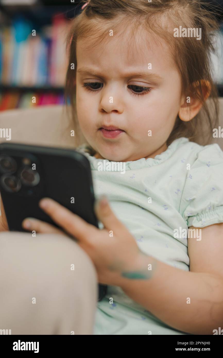 Adorable baby girl trying to use smartphone for watching cartoon. Baby ...